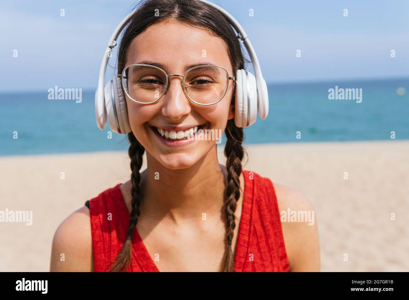 Portrait of happy female in headphones listening to music on sandy ...