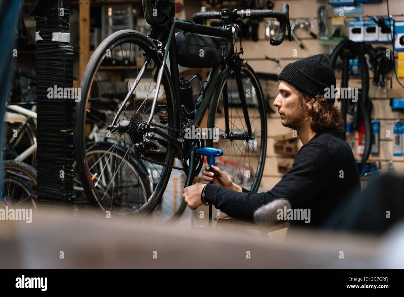 Side view of young skilled male mechanic with tool assembling chain ...