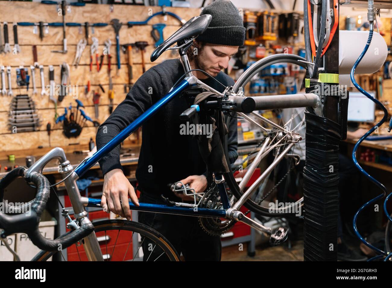Side view of serious male mechanic repairing wheel of bicycle while ...