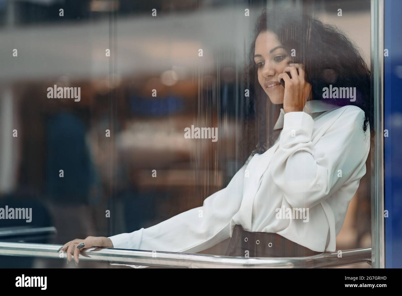 close-up. young woman with a smartphone climbing in a glass elevator ...