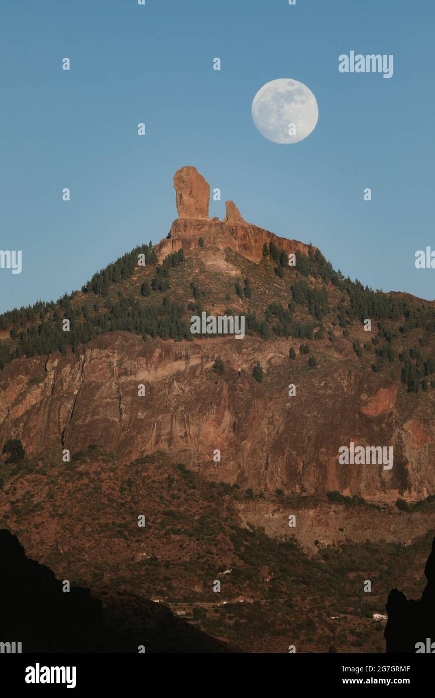 Spectacular landscape with large full moon in blue sky over rocky ...