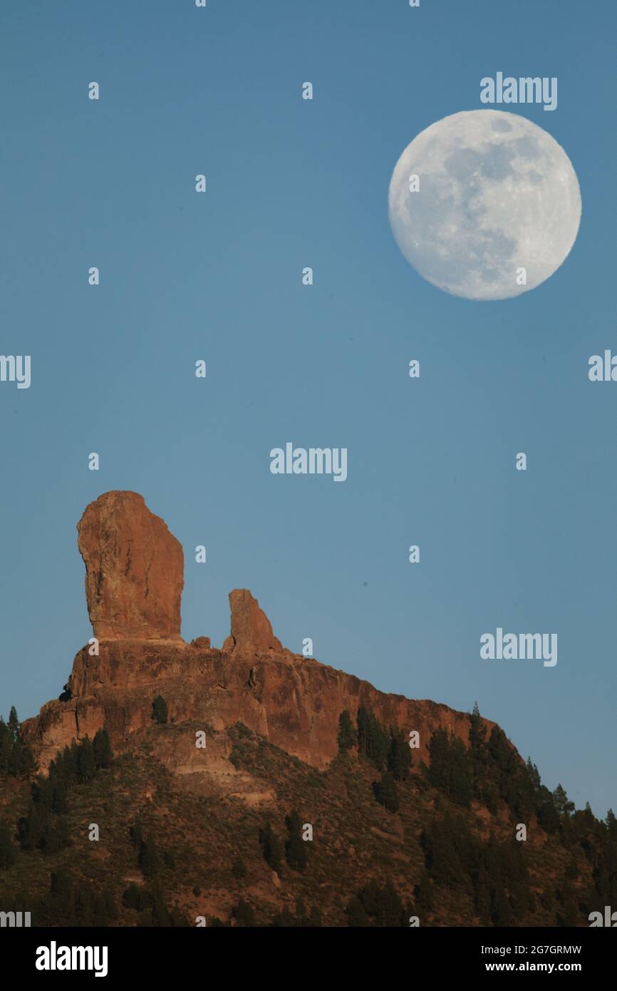 Spectacular landscape with large full moon in blue sky over rocky ...