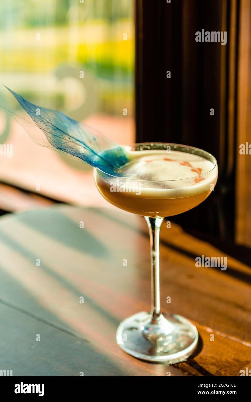 Creative fancy bright yellow alcoholic drink served in cocktail glass ...