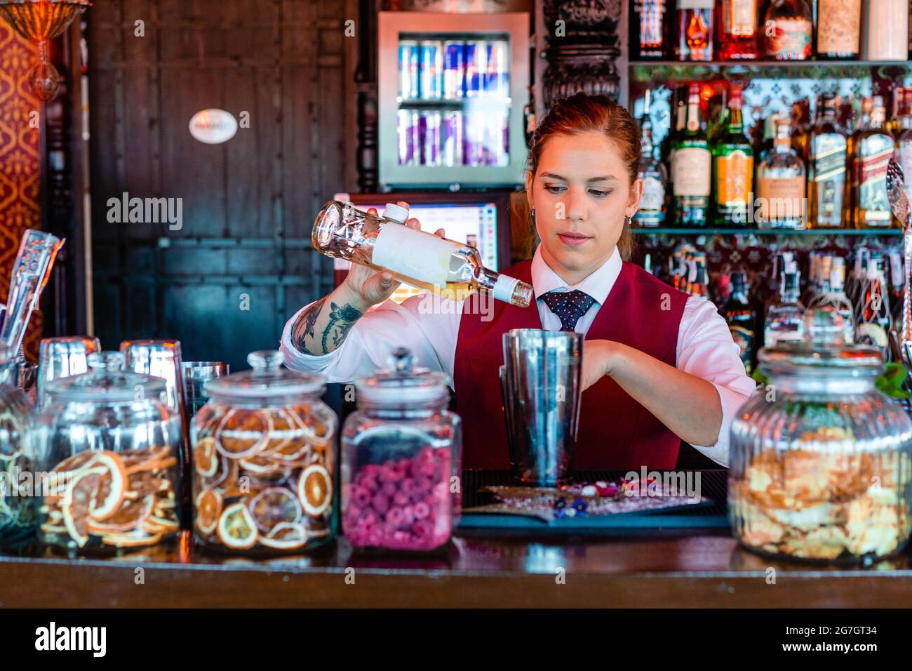 Female barkeeper pouring alcohol in shaker while preparing refreshing ...