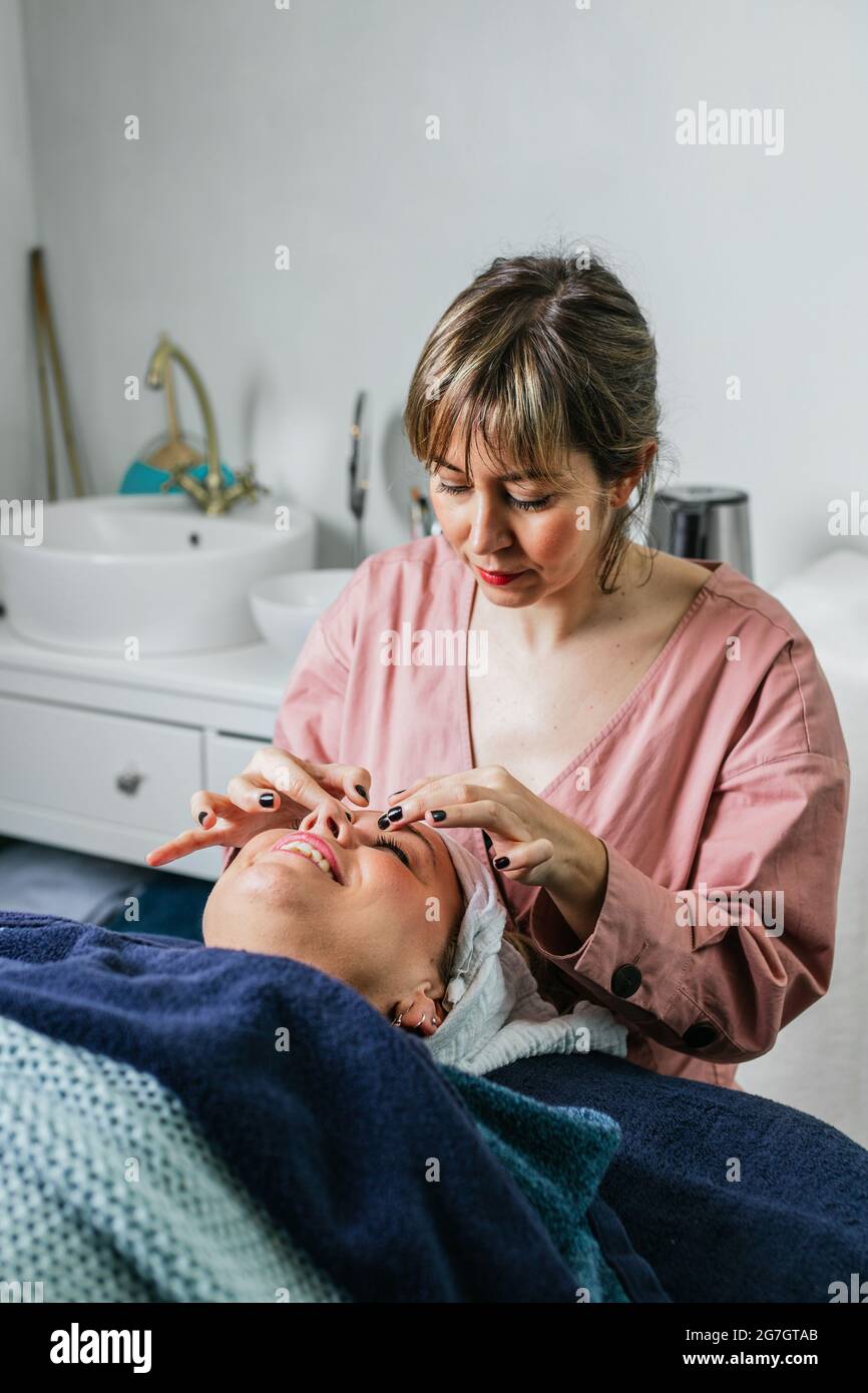 Content Masseuse Massaging Shoulders Of Female Client Lying On Table In