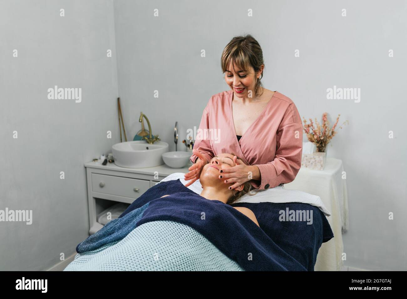Content masseuse massaging shoulders of female client lying on table in ...