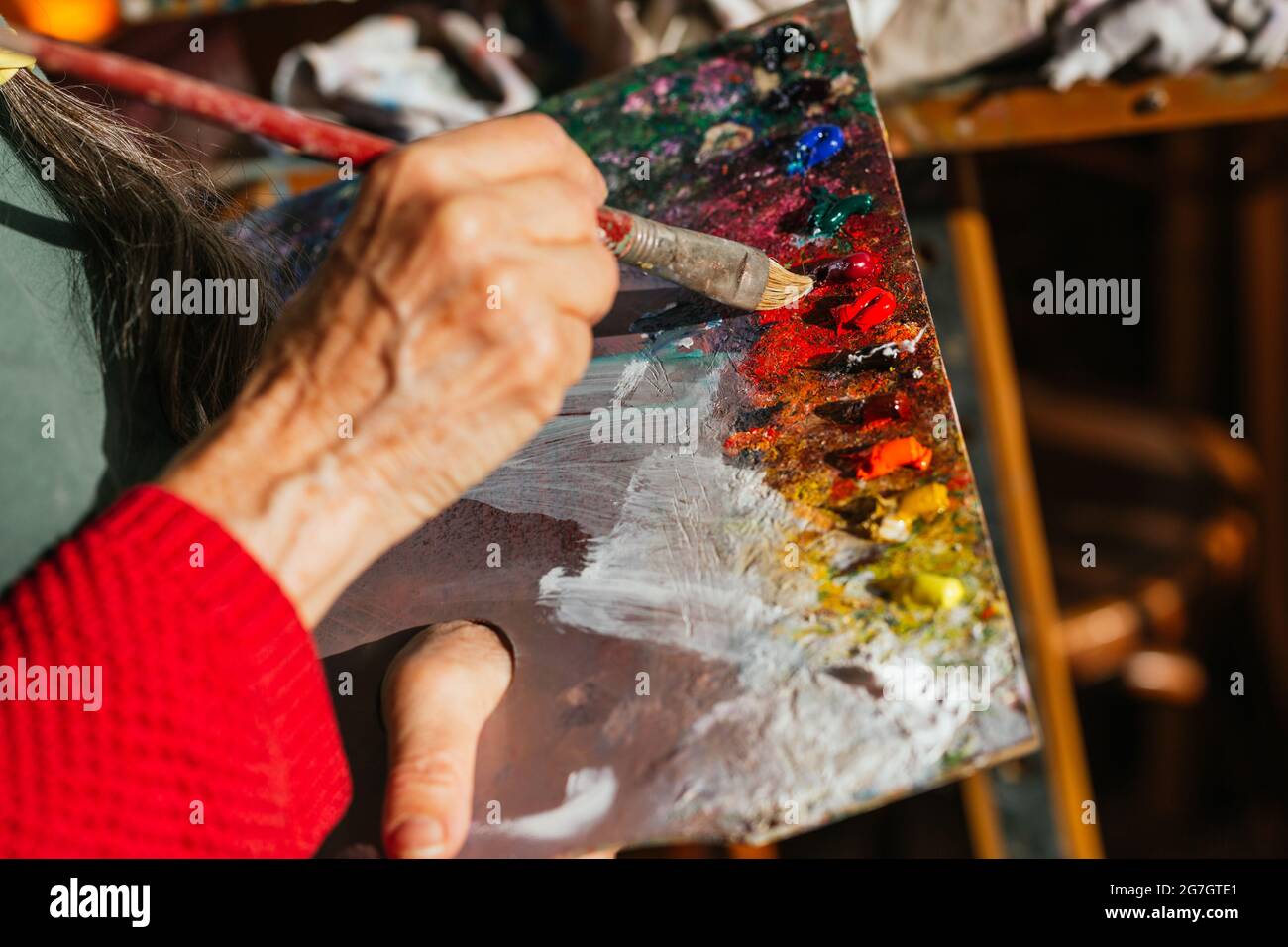 From above of crop unrecognizable senior female painter mixing colors ...