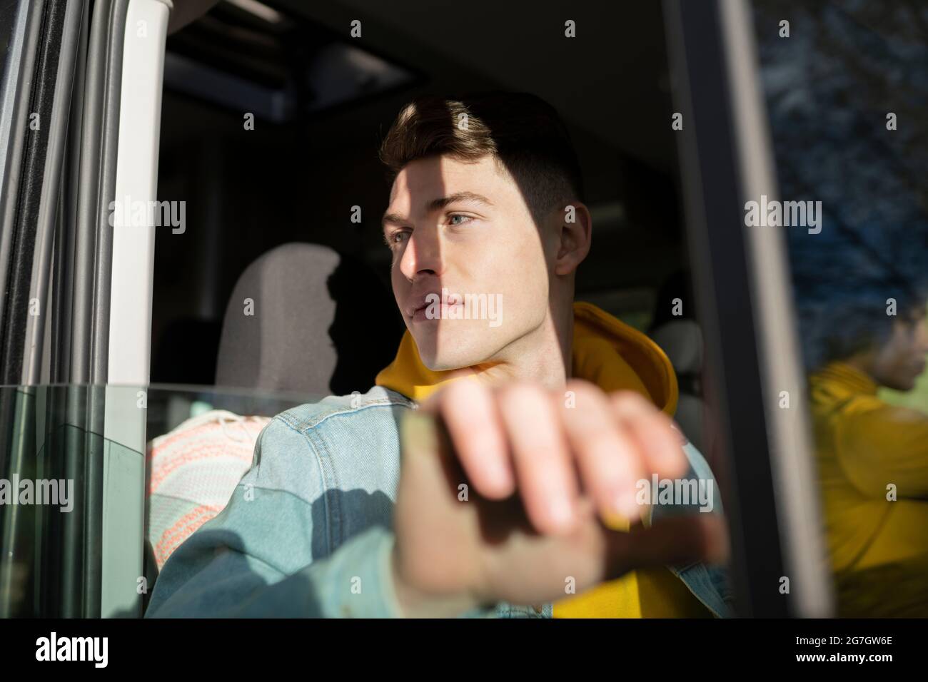 Young man looking out window while riding modern vehicle during road ...