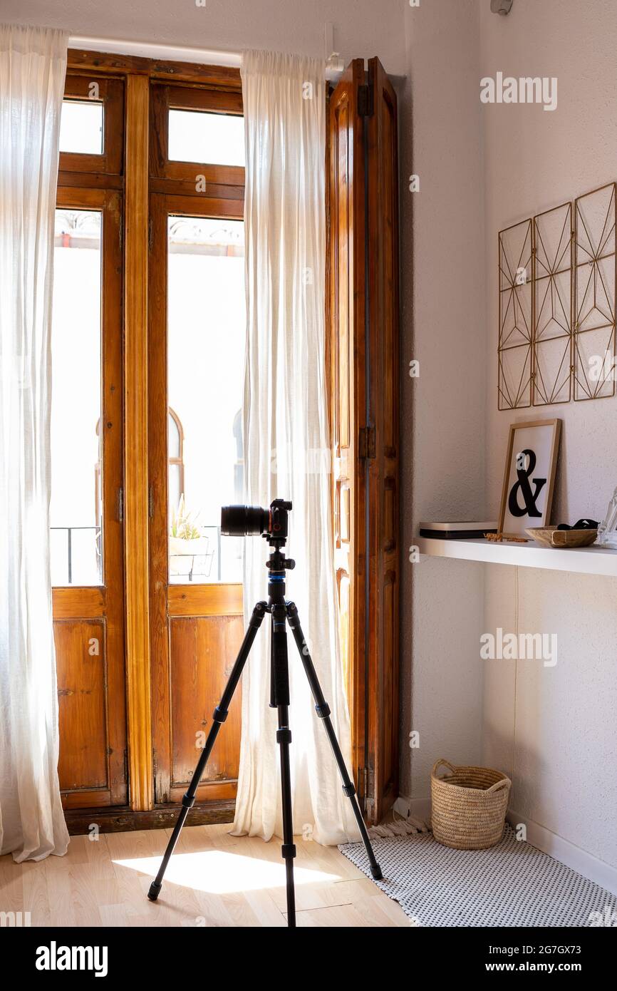 Modern photo camera on tripod placed in room of cozy apartment with ...