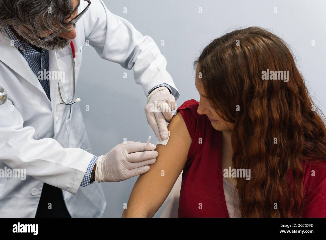 Aged male medic putting patch on arm of female patient after injection ...