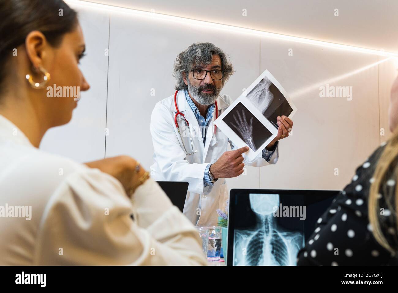Elderly male medic explaining x ray image to coworkers while working in ...