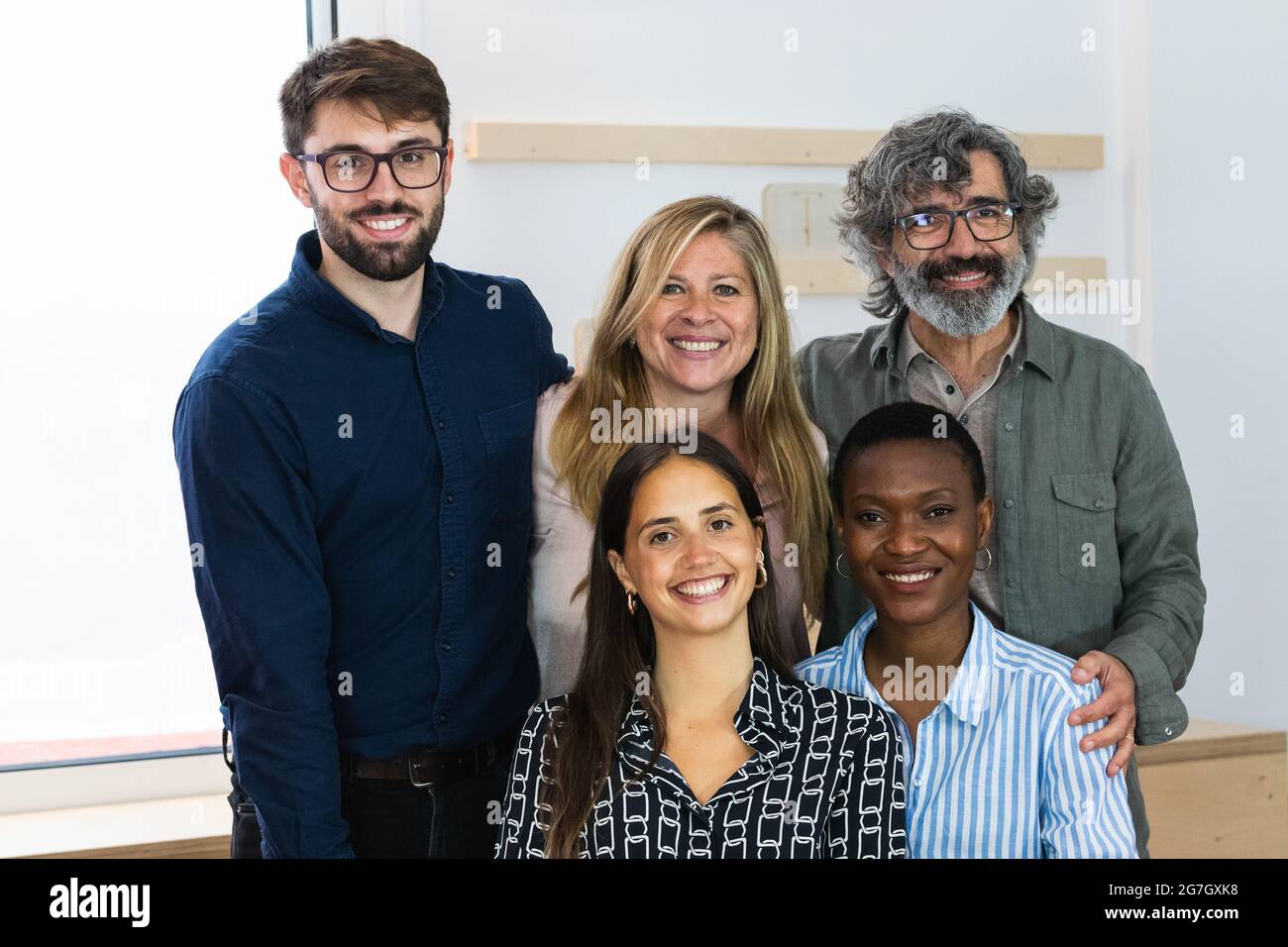Delighted multiracial female colleagues looking at camera and smiling ...
