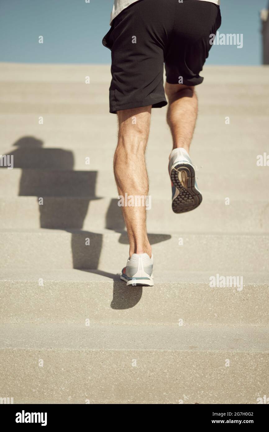 Back view of cropped unrecognizable athletic male running upstairs ...