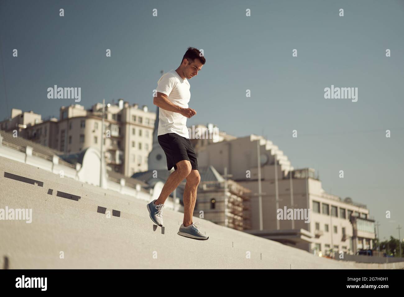 Side view of athletic male running downstairs while training on sunny ...