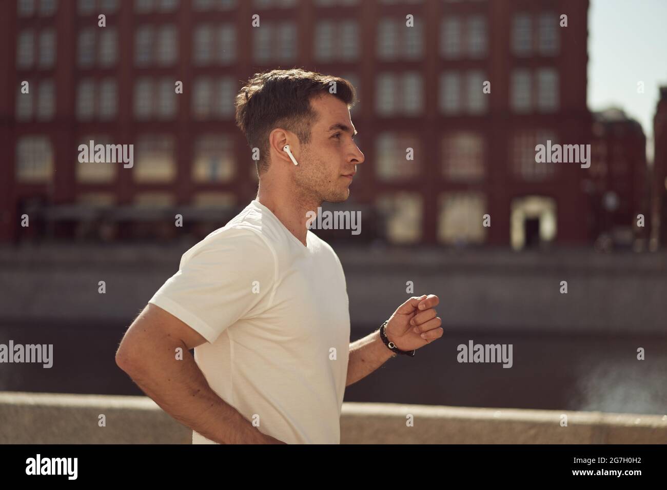 Side view of strong male athlete running along street during active ...