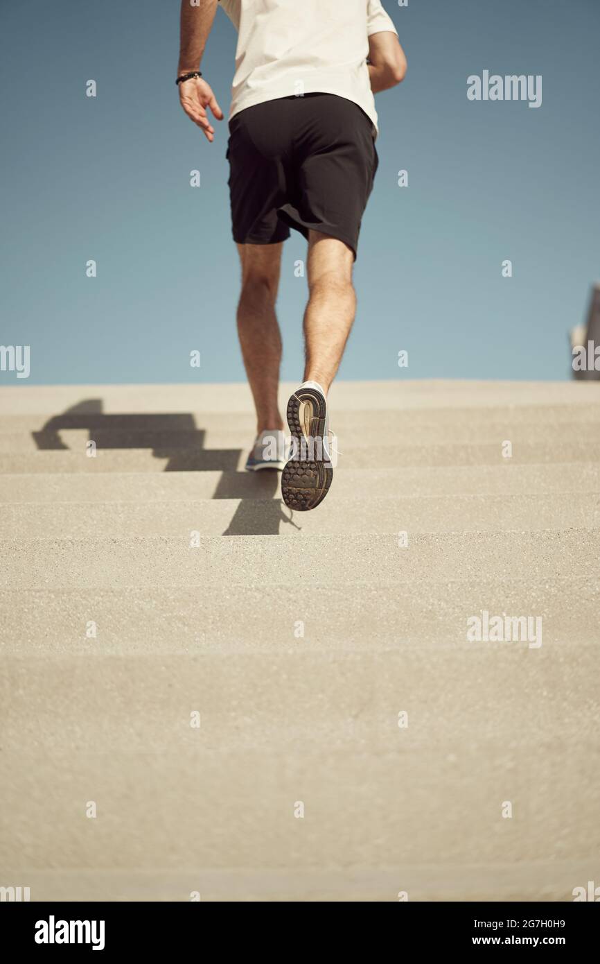 Back view of cropped unrecognizable athletic male running upstairs ...