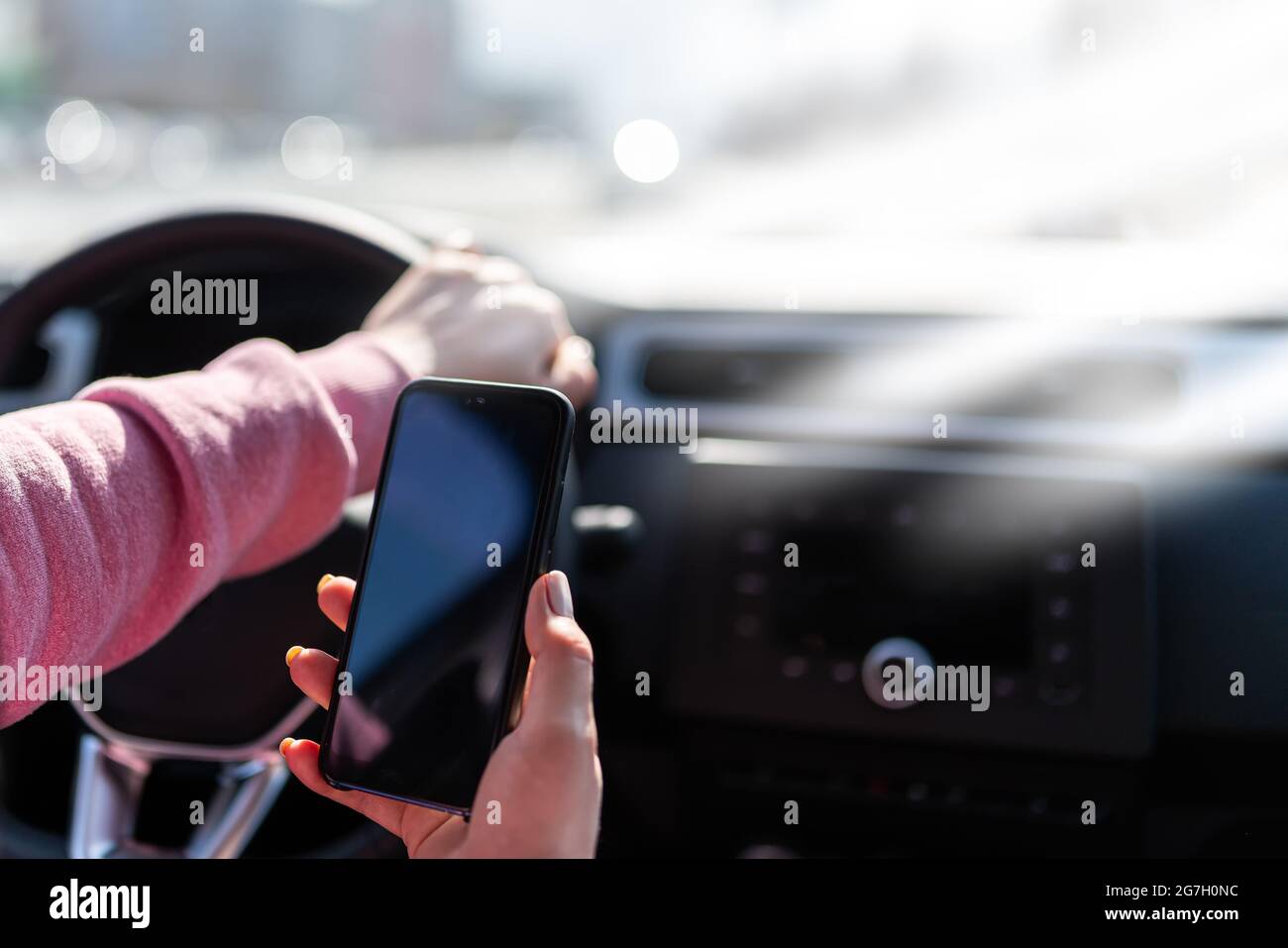 Hand holds the cell phone against the background of the steering wheel ...