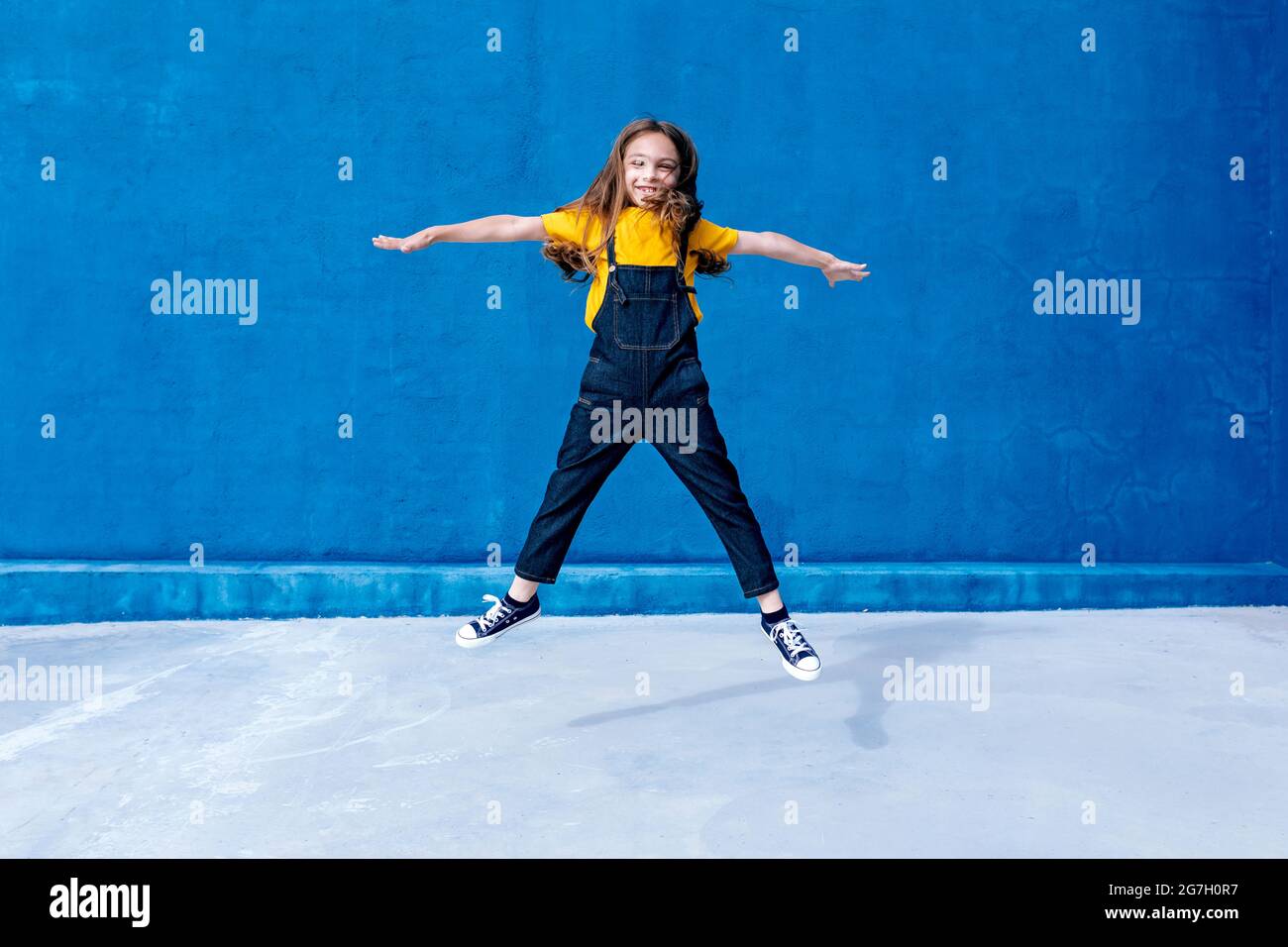 Carefree smiling teenager in moment of jumping above ground with ...