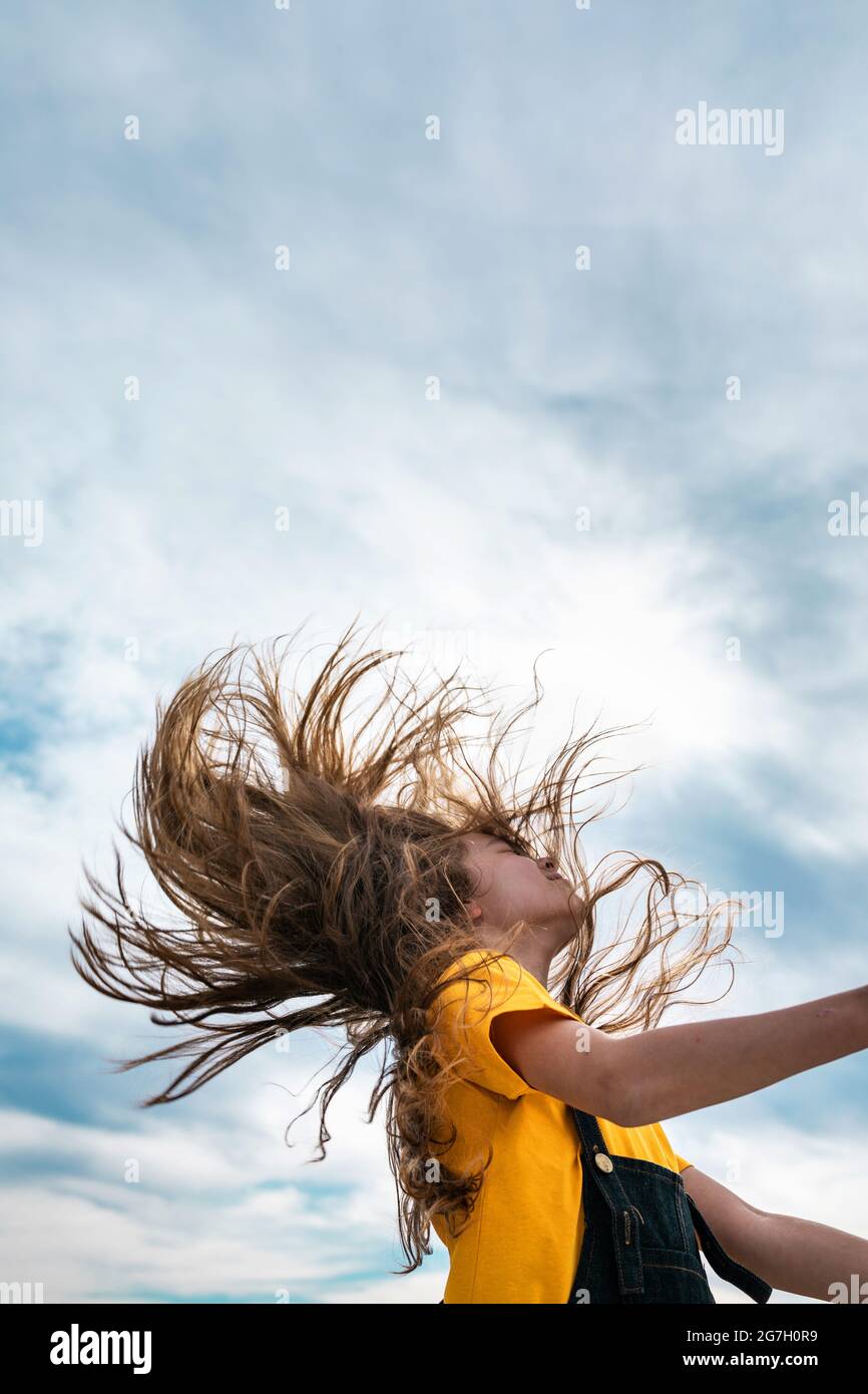Side view from below of peaceful teenager throwing long hair on ...
