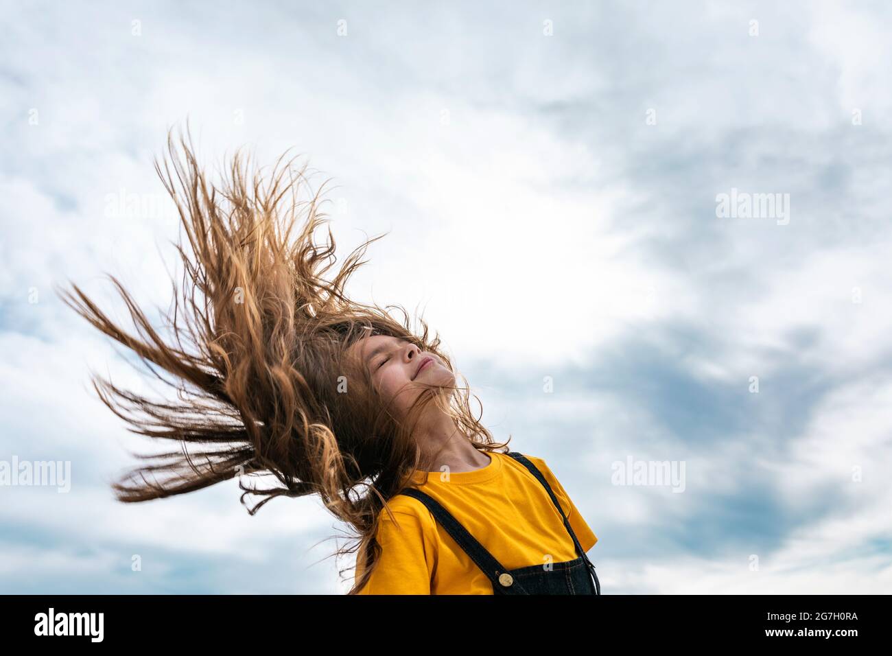 Side view from below of peaceful teenager throwing long hair on ...