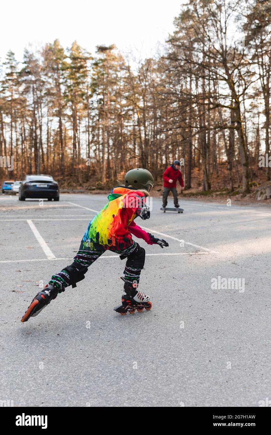 Back view of active anonymous kid in helmet rollerblading on parking in ...