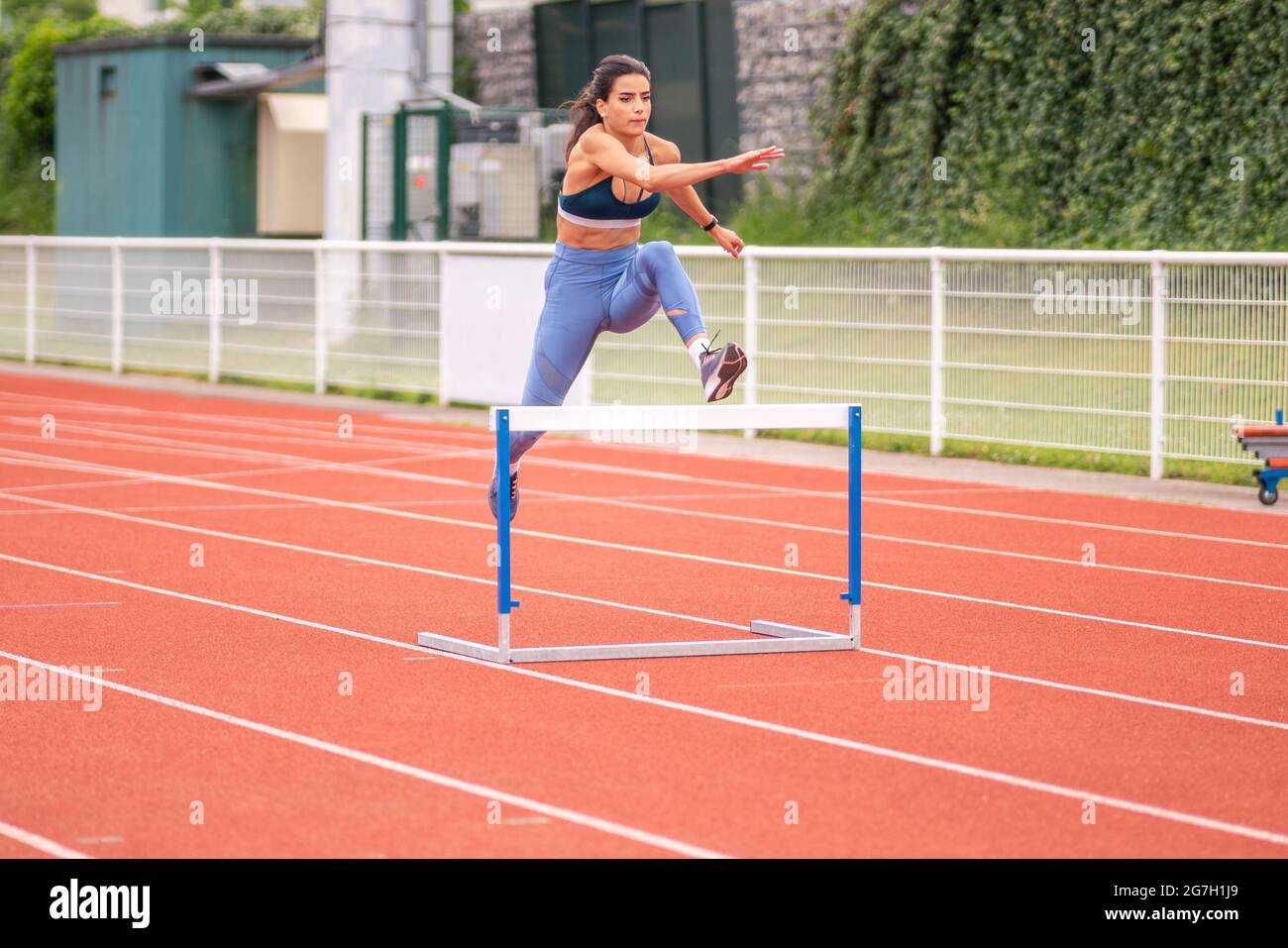 Full length of confident young Hispanic sportsWoman jumping over ...
