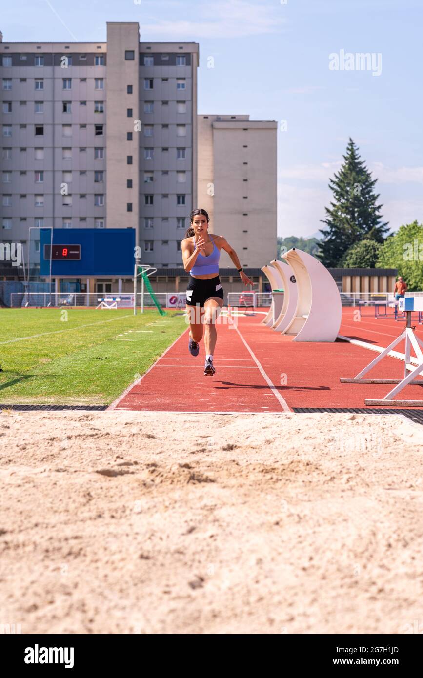 Full body of determined young female track and field athlete running ...