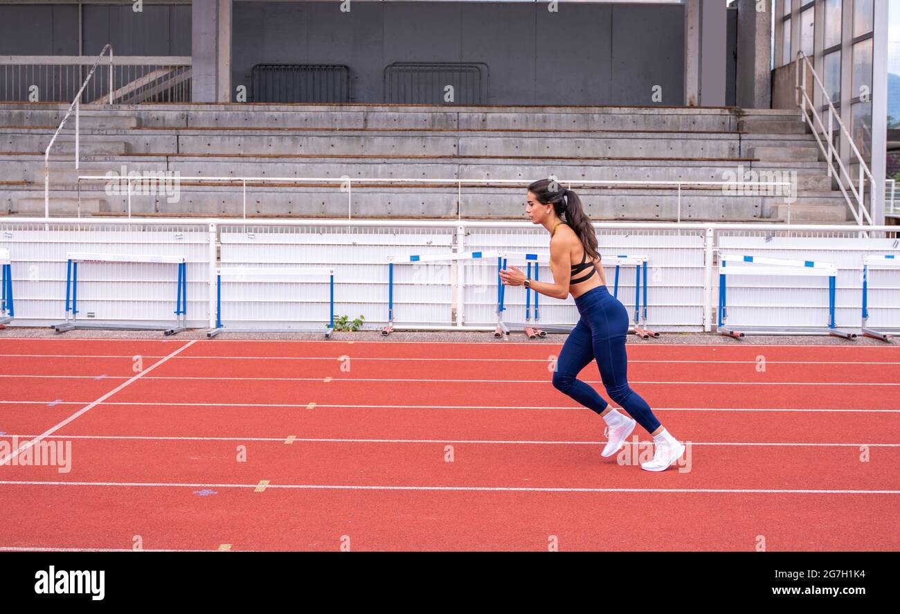 Side view of female athlete running at stadium during track and field ...