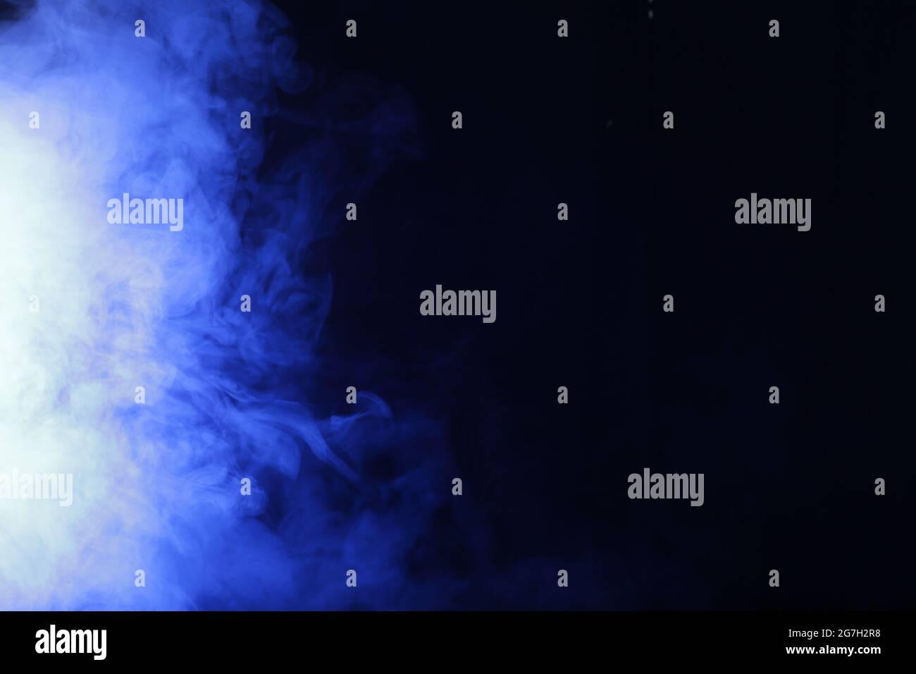 Magic smoke in blue light on black background Stock Photo - Alamy