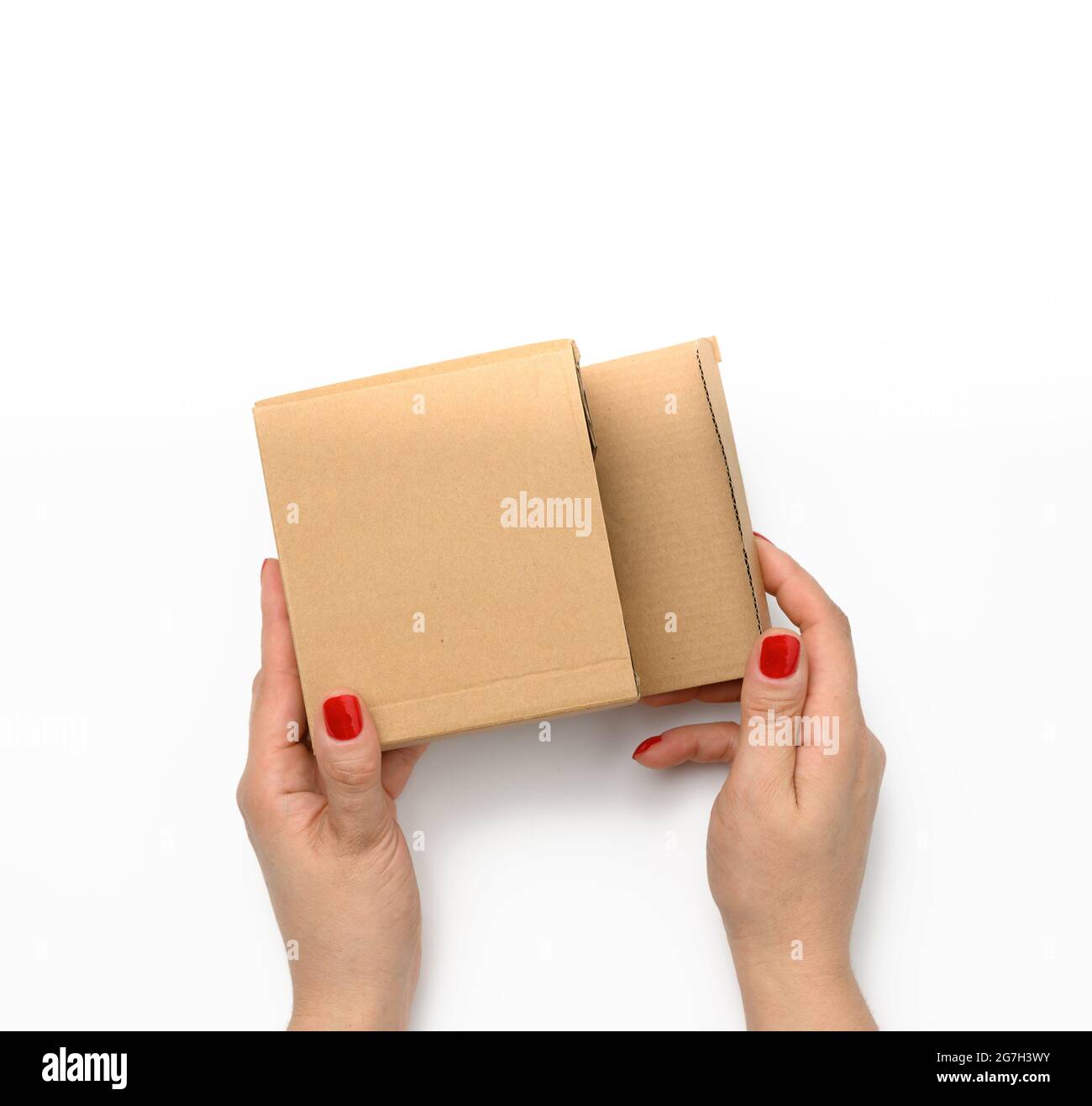 two female hands hold a square box made of brown corrugated cardboard ...