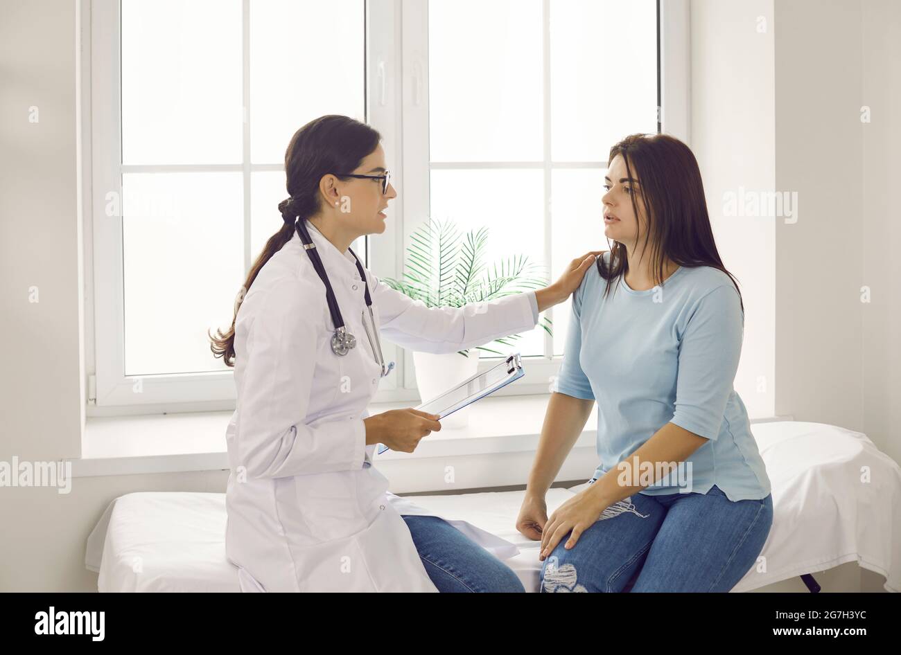 Doctor reassuring and supporting young woman while talking to her about ...