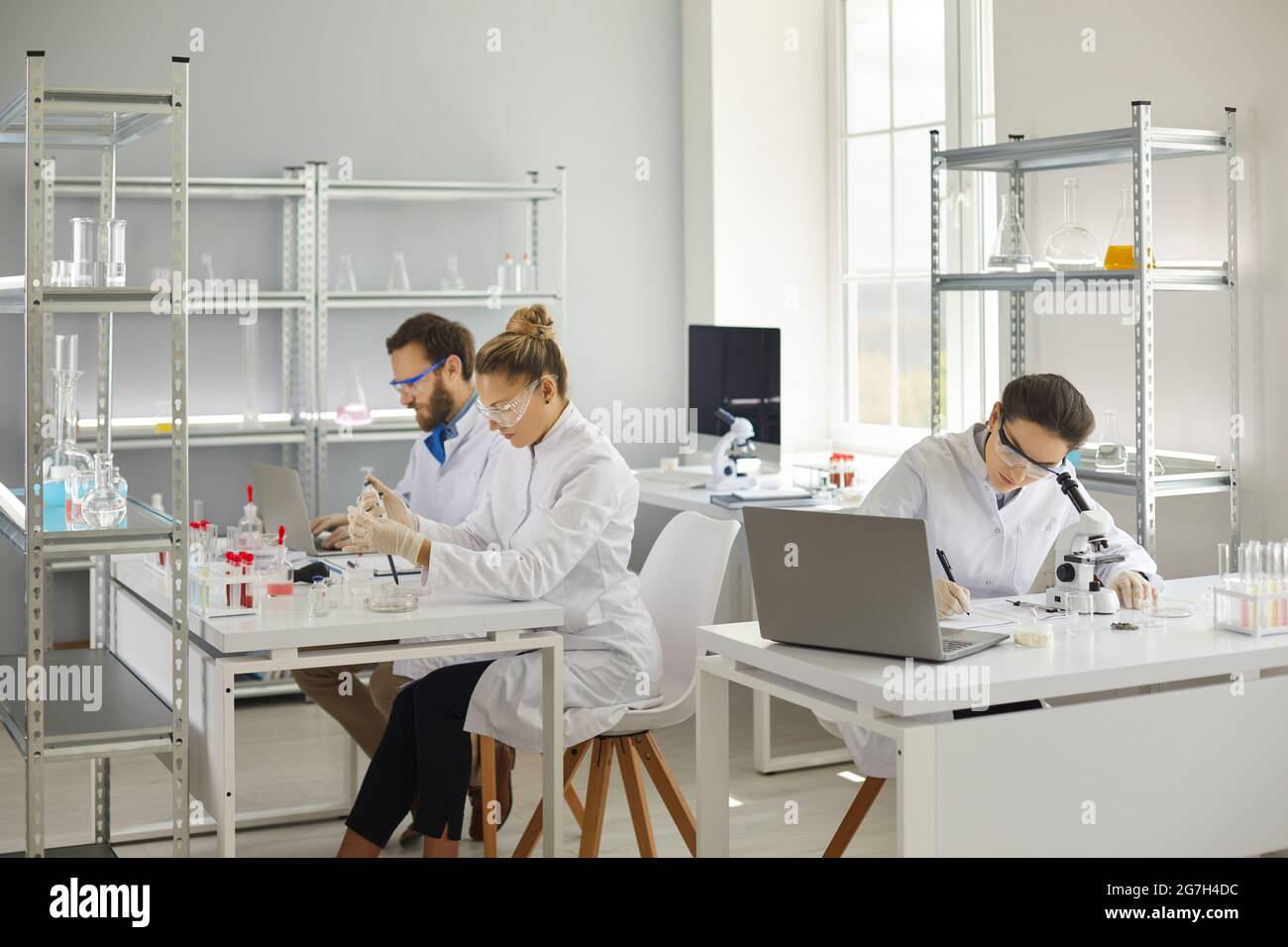 Group of busy medical scientists working in modern pharma or biotech ...