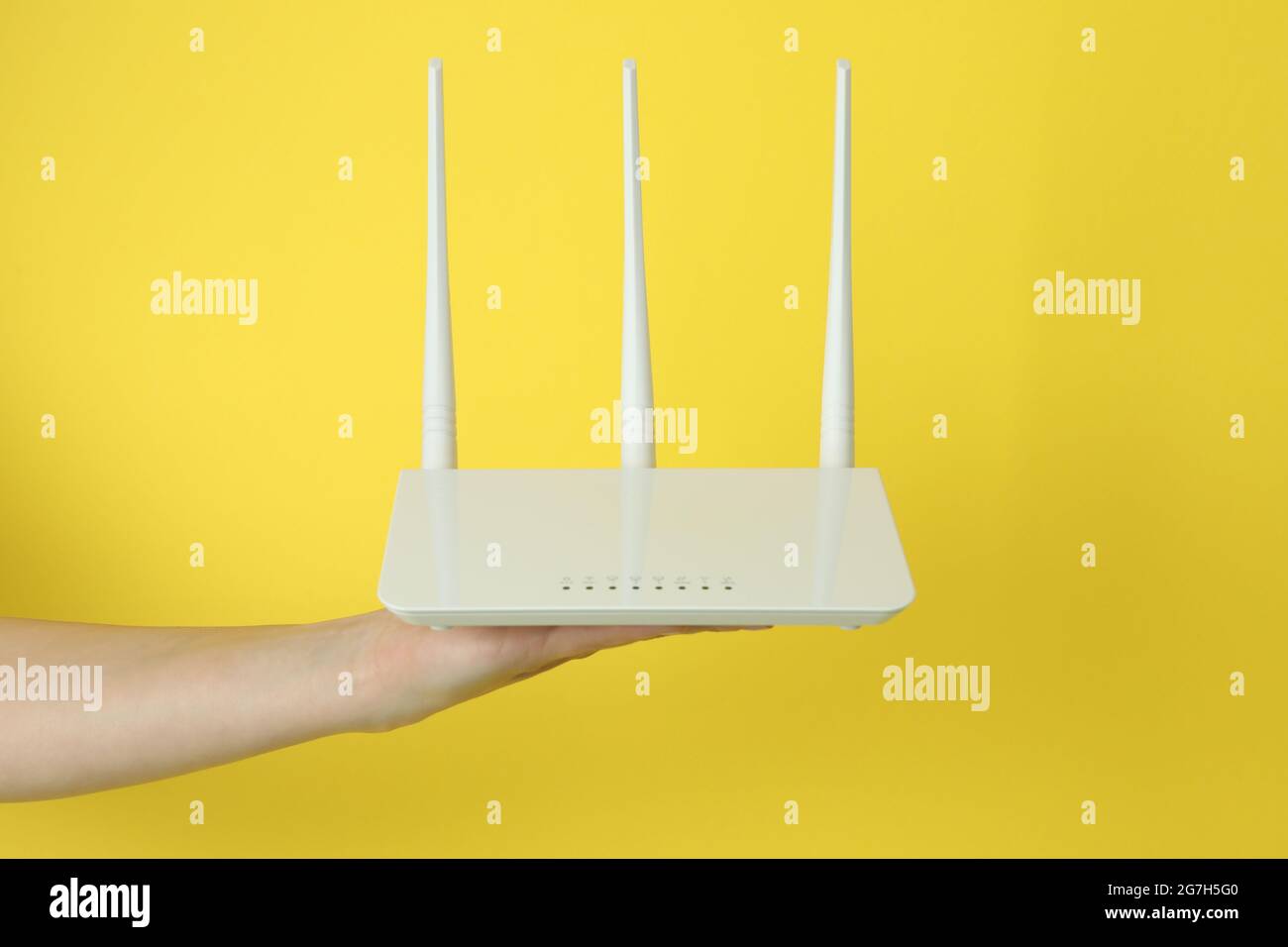 Female hand holds Wi - fi router on yellow background Stock Photo - Alamy
