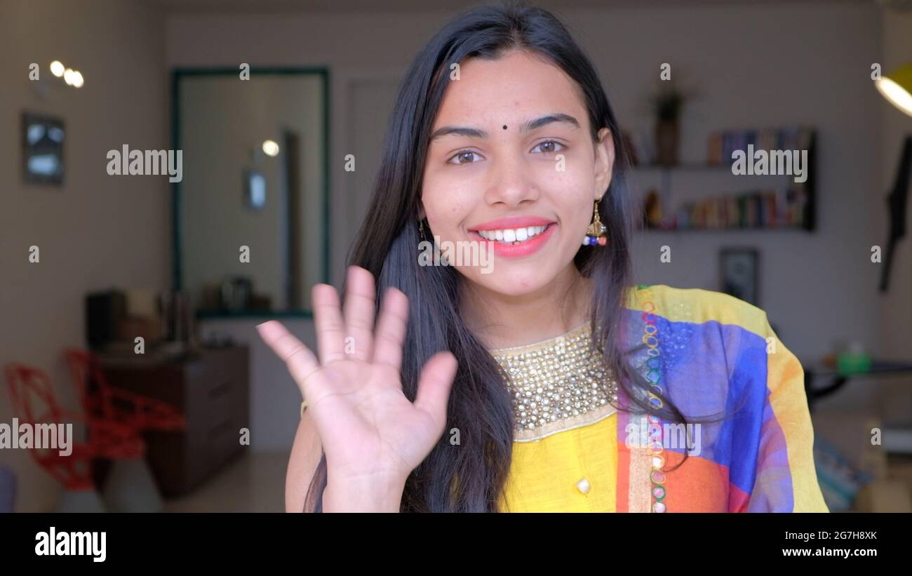 Attractive young Indian female in a traditional sari saying hi at home ...