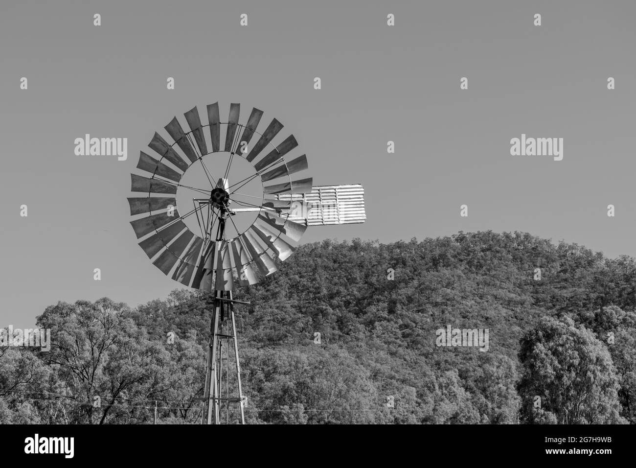 Grayscale shot of an old metal windmill against mountain trees Stock ...