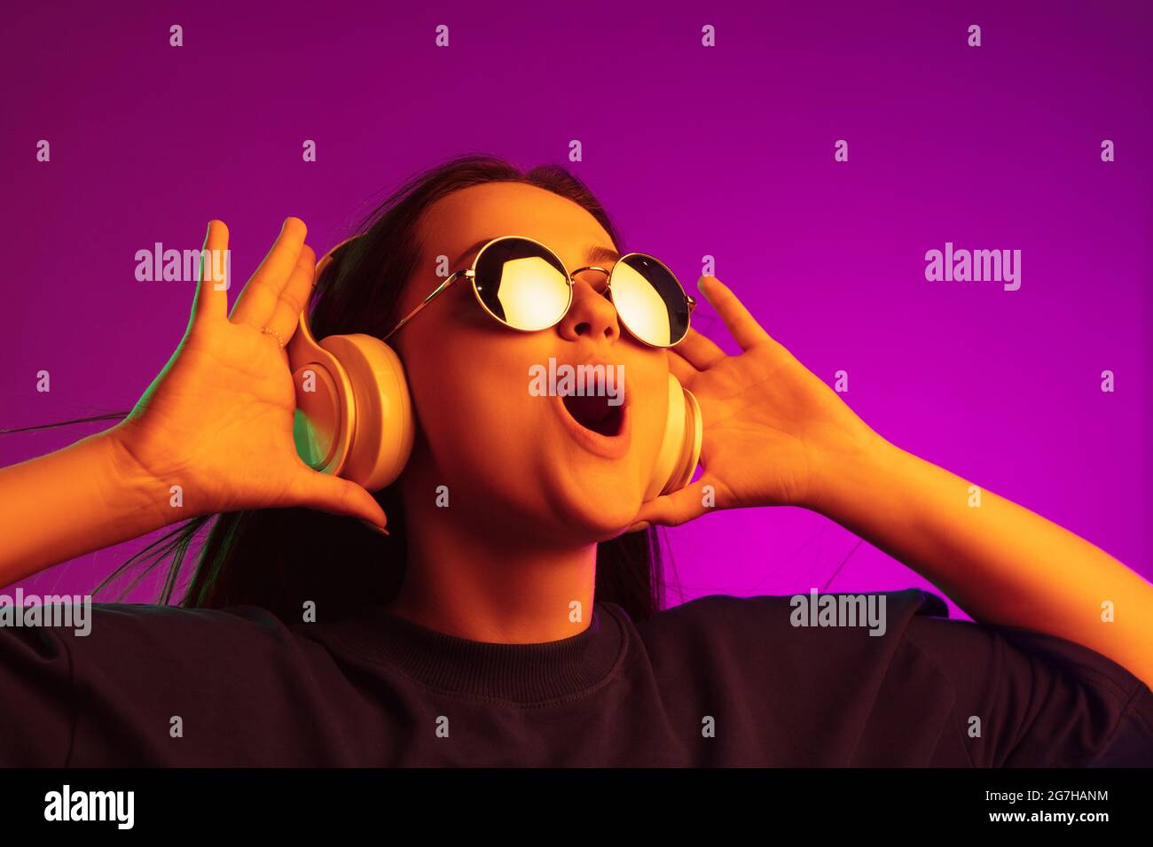 Enjoying music. Young beautiful caucasian girl in headphones and bright ...