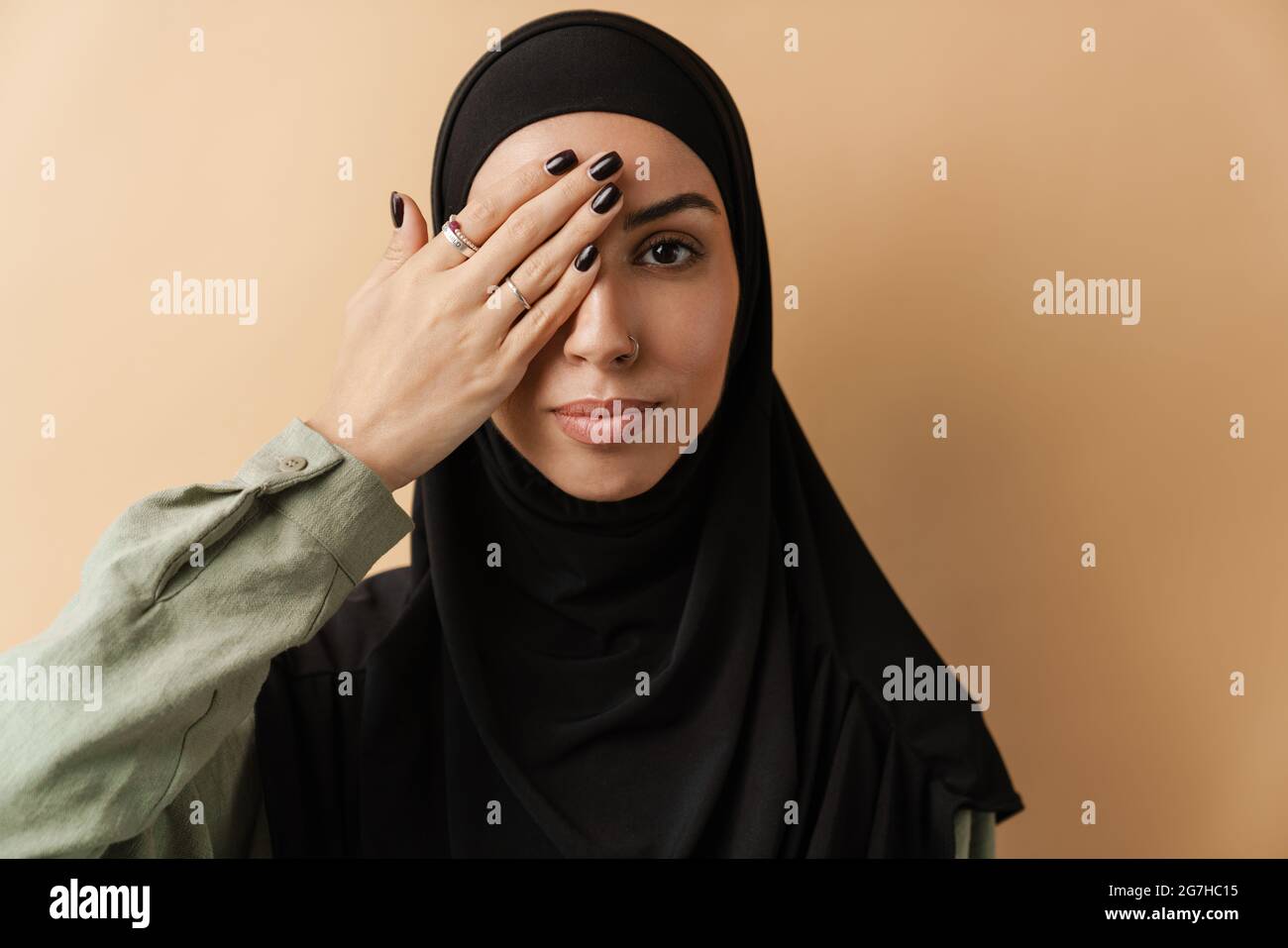 A portrait of the muslim woman covering her eye with one hand while ...