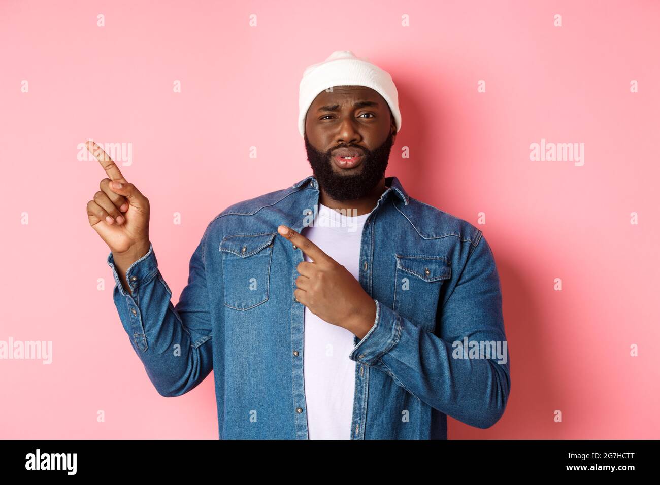 Skeptical and doubtful Black man staring at camera unsure, pointing ...