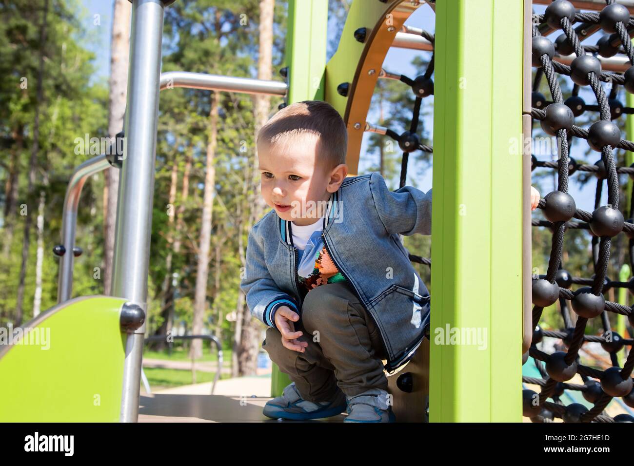 Caucasian little boy climbs the slide on his own to slide down in the ...