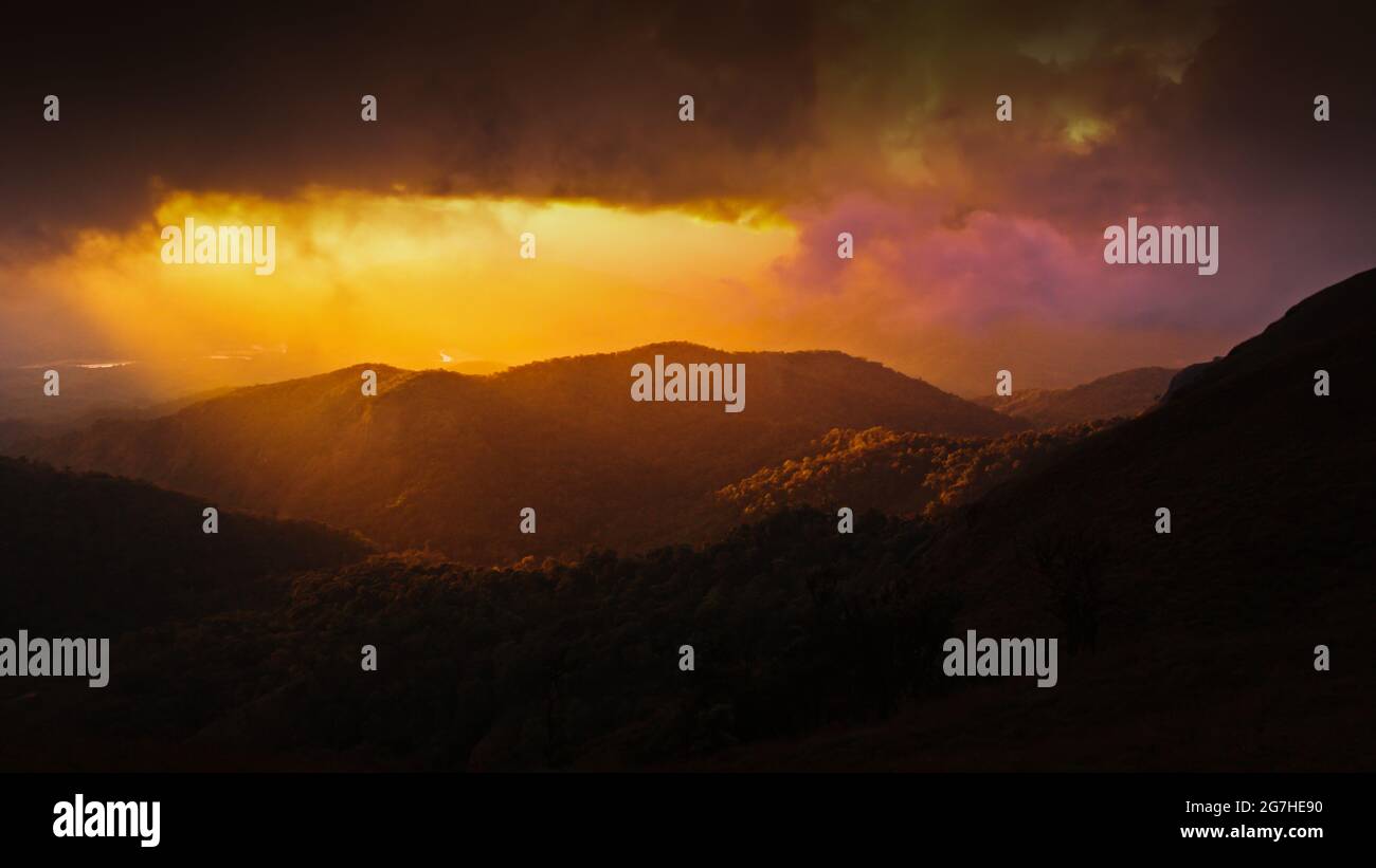 Dramatic rainstorm hiding the setting sun and mountain ridge, magical ...