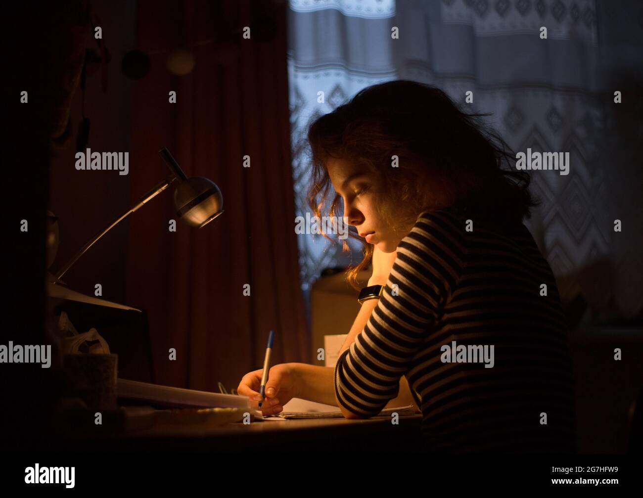 beautiful young woman, teenage girl, student, schoolgirl sits at a desk ...