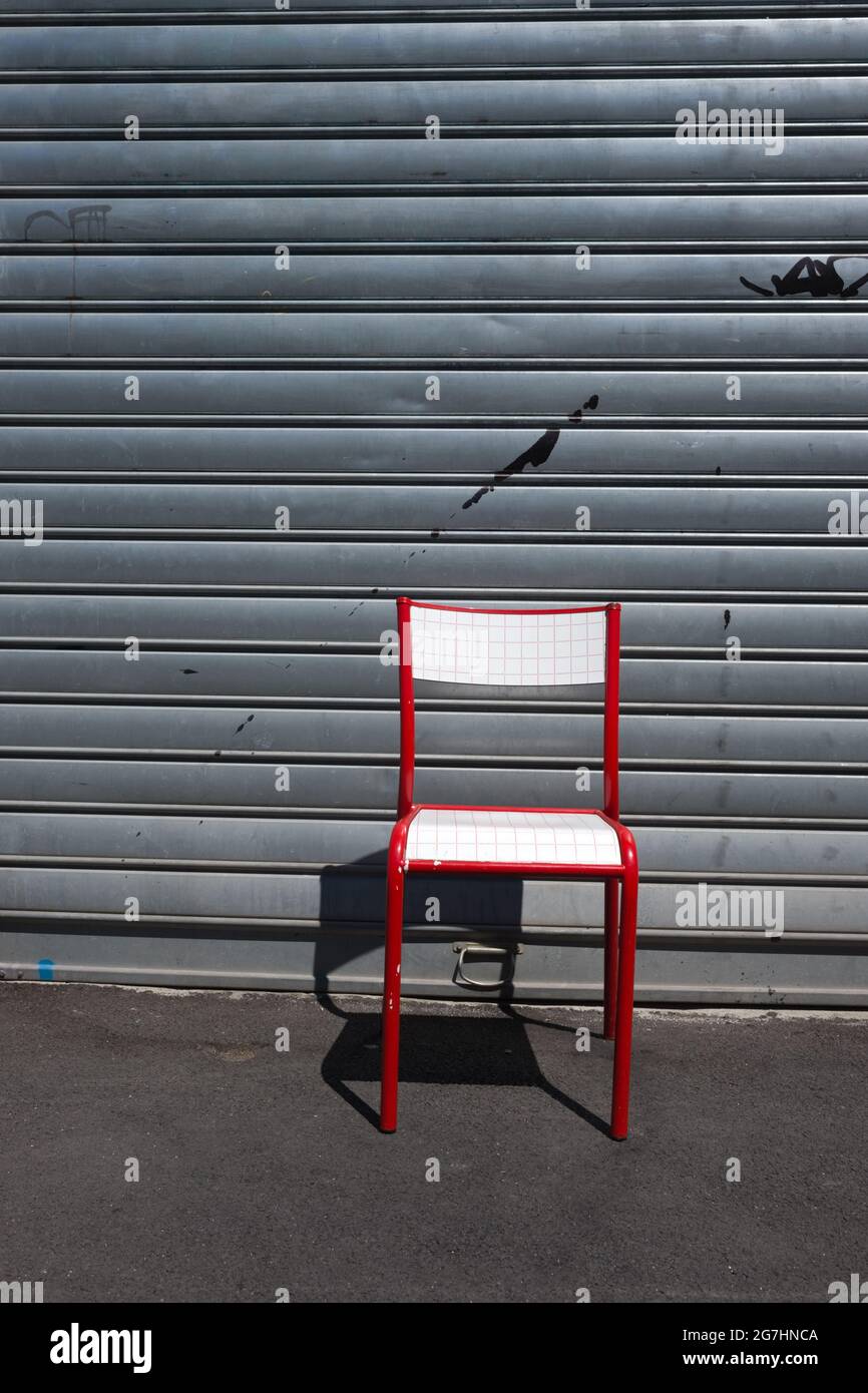 a single abandoned red and white metal chair with geometrical pattern ...