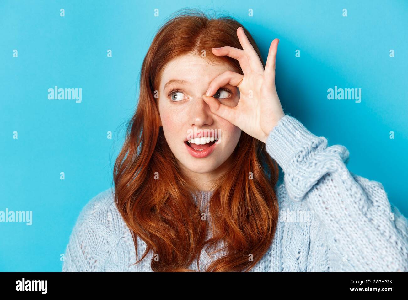 Headshot of pretty redhead girl in sweater, looking left at promo with ...