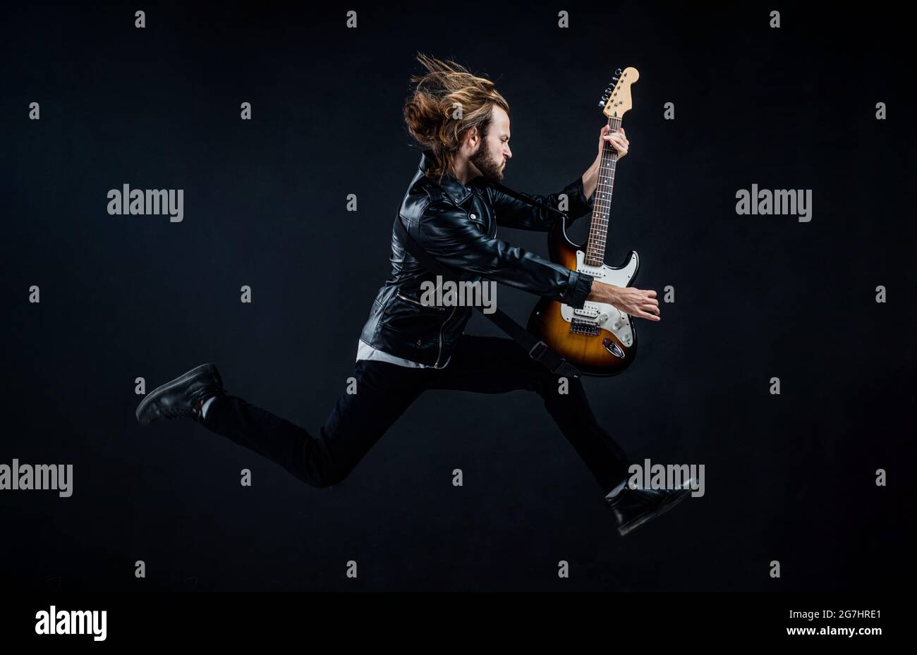 emotional bearded rocker in leather jacket. man long hair play electric ...