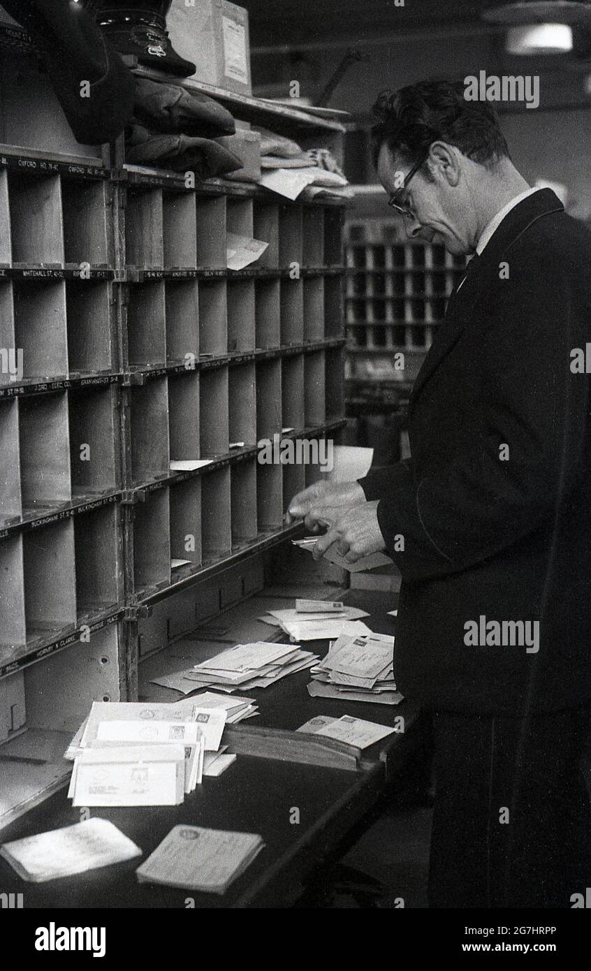 1950s, historical, a male GPO worker sorting out letters or mail into ...
