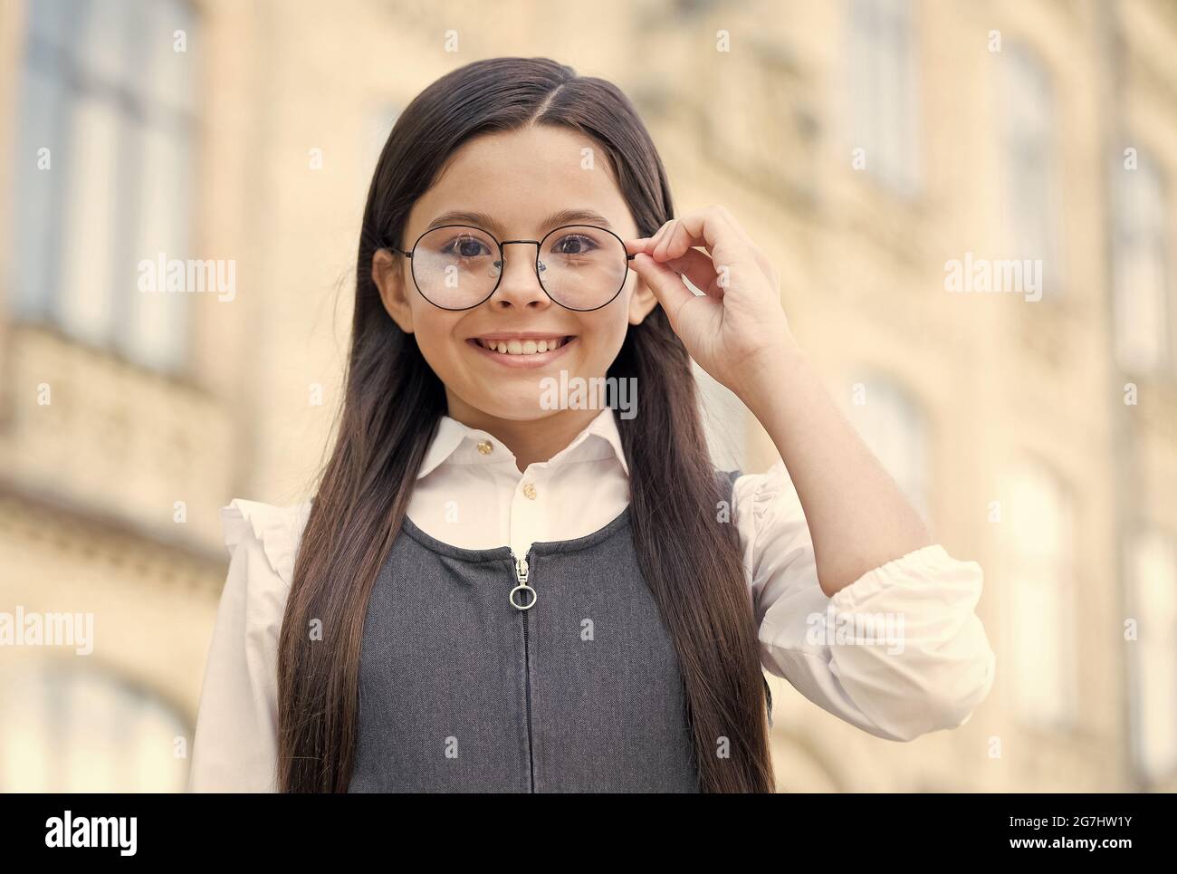 Happy girl child wearing school uniform fix eyeglasses in fashion frame ...