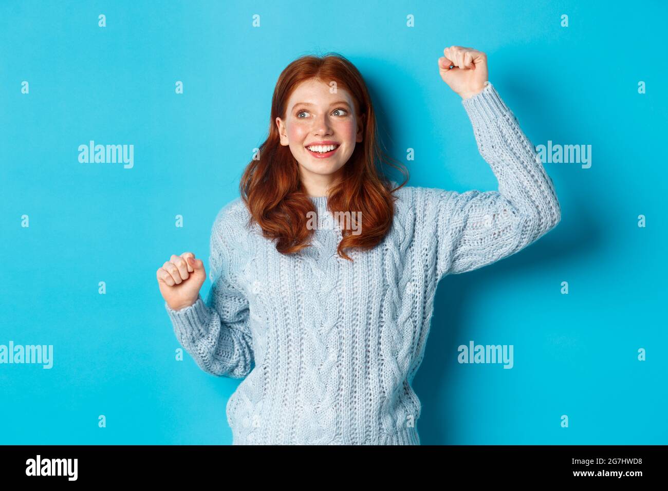 Happy redhead girl rooting for team, cheering with raised hand and ...