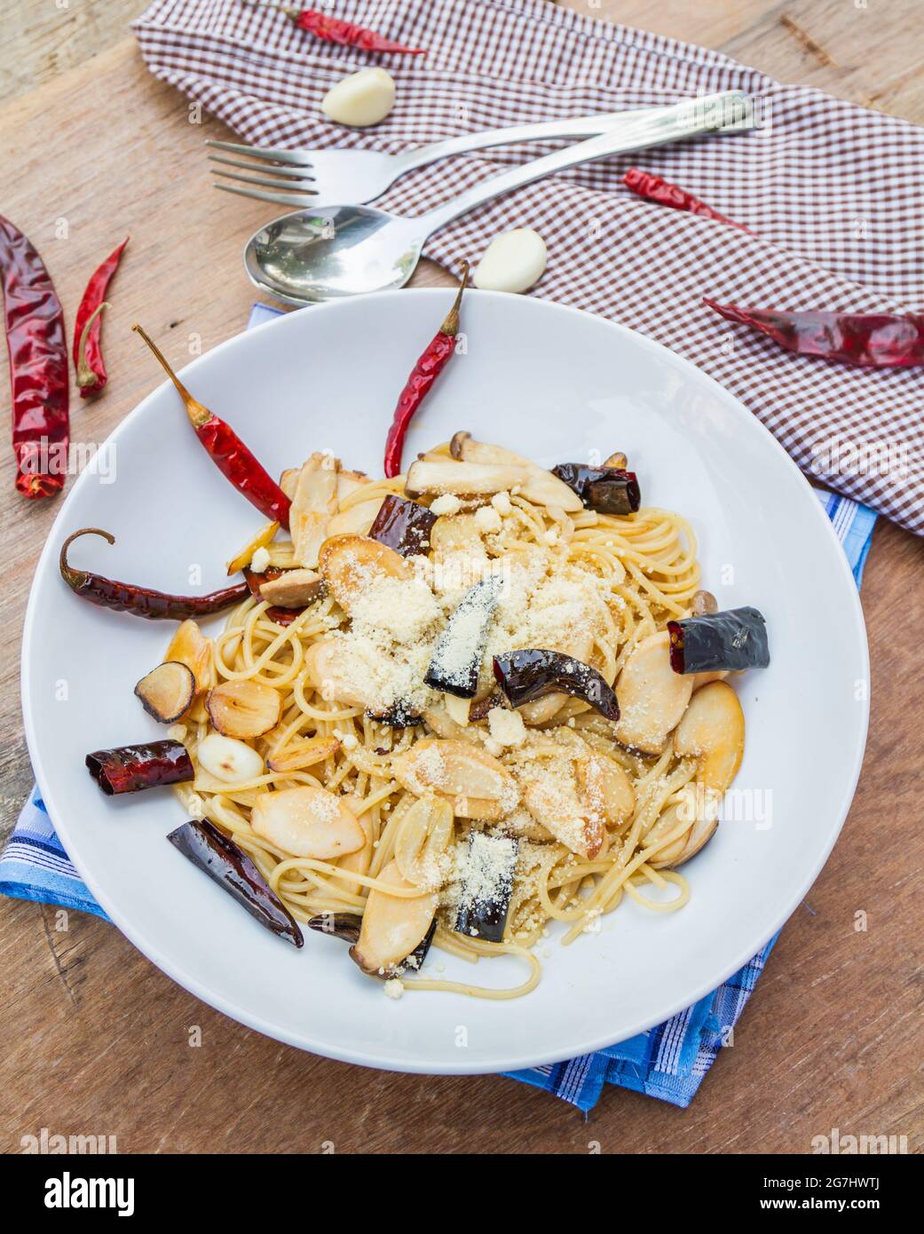 Spaghetti stir dried chili add eringi mushroom on white dish on wooden table Stock Photo - Alamy