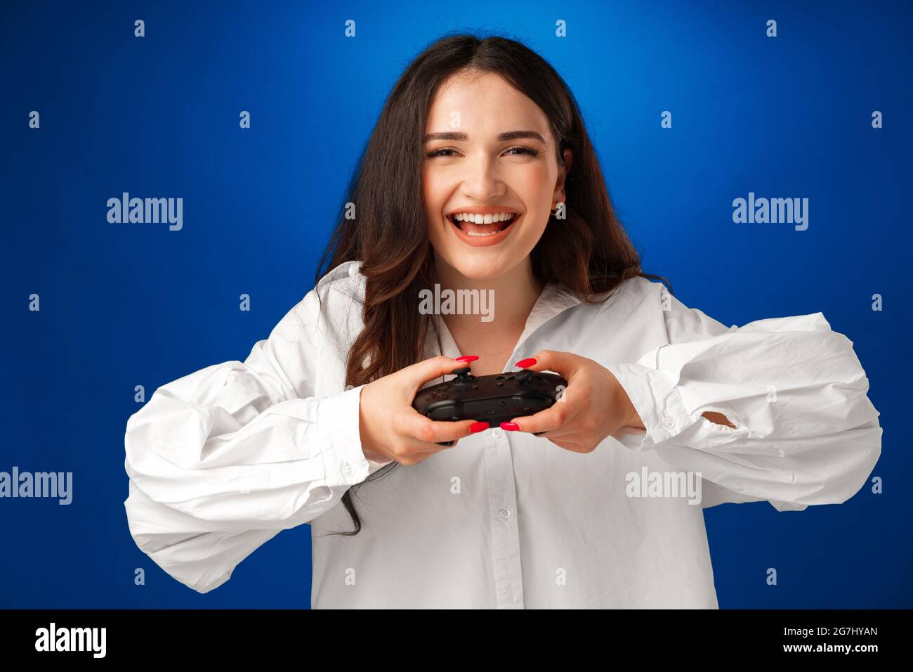 Beautiful brunette girl playing video games against blue background ...