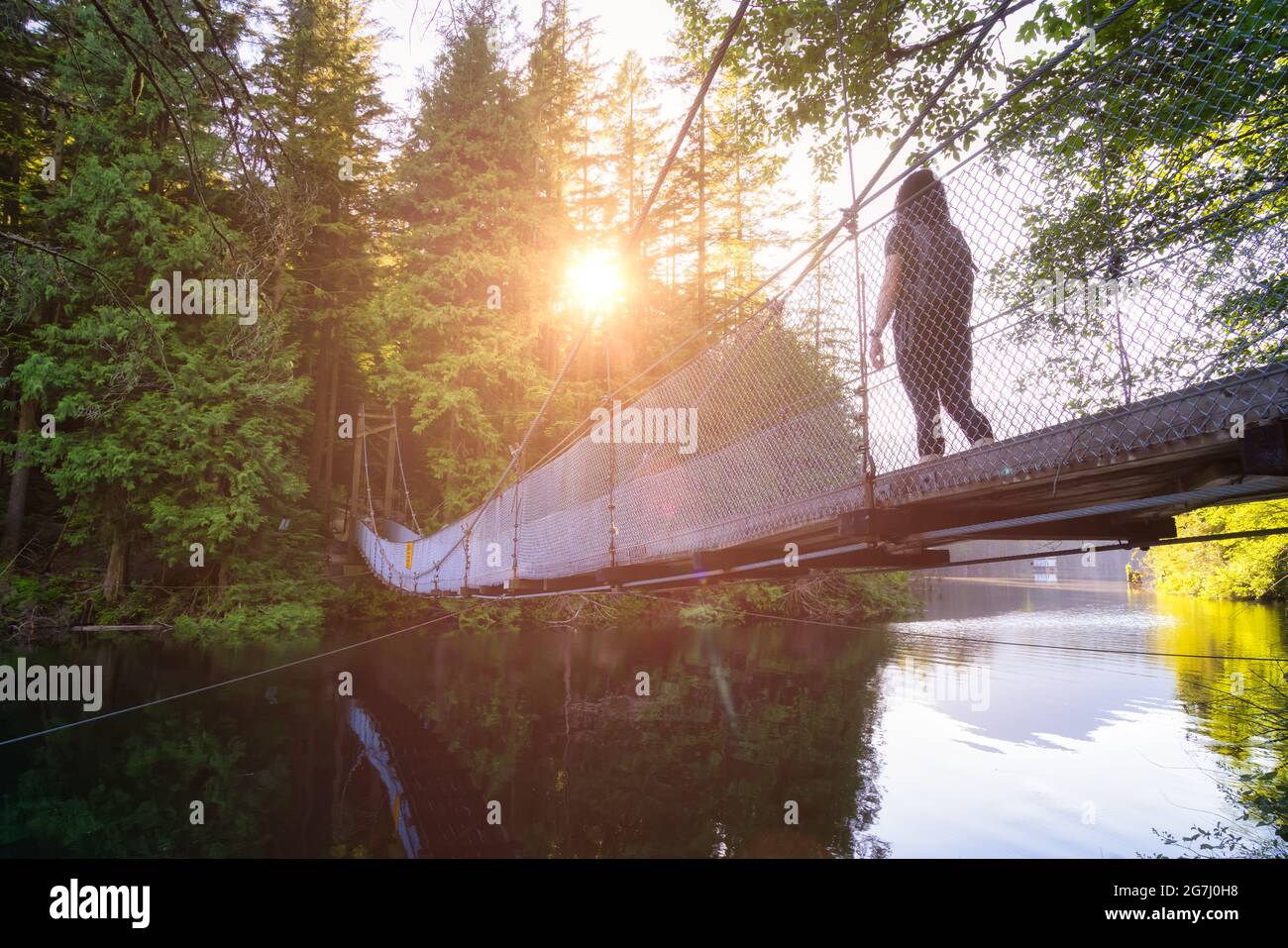 Woman Walking on Suspension Bridge over the water Stock Photo - Alamy